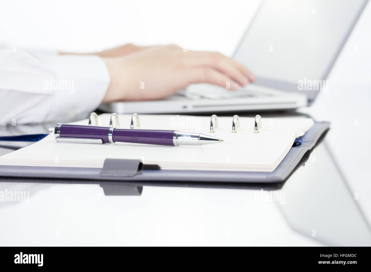 Businessman write a short note on opened notebook with pen and glasses ...