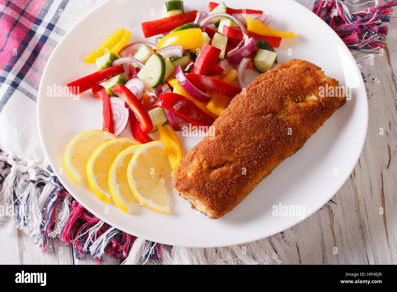 fried fish fillet with fresh vegetable salad on the plate closeup ...