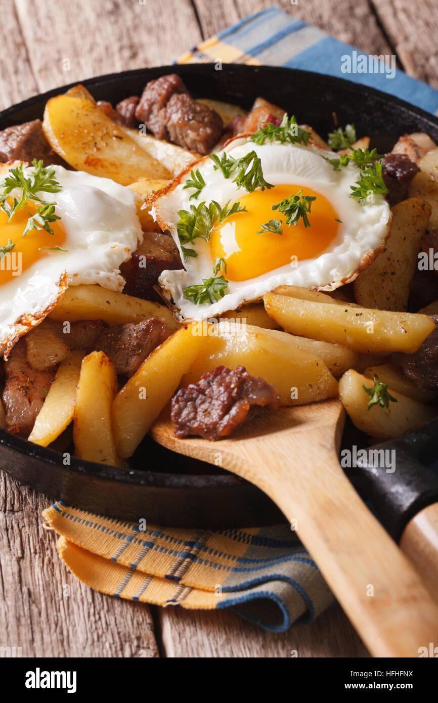 Austrian food: fried potatoes with meat, ham and eggs in a pan close-up ...