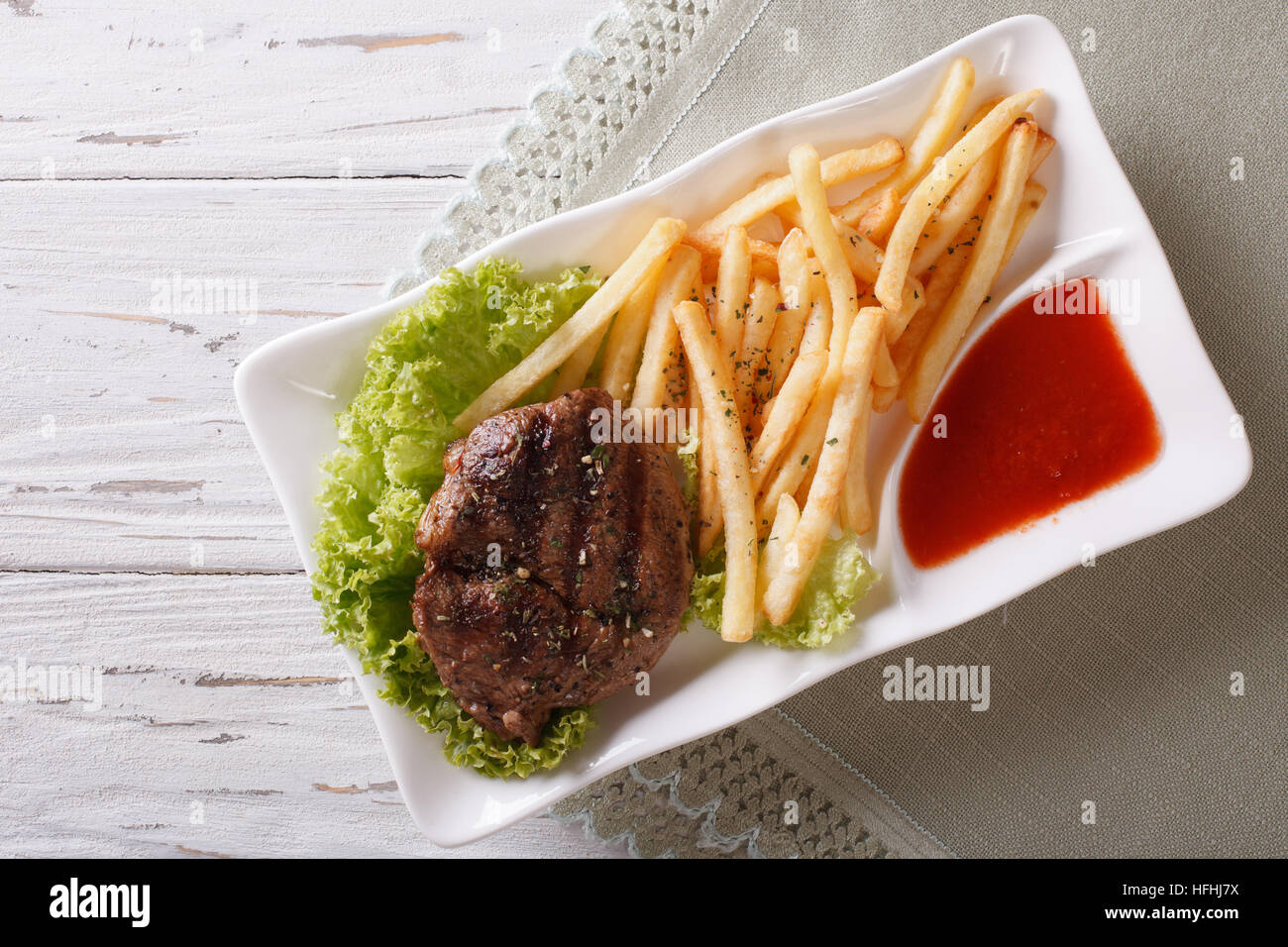 Serving grilled beefsteak with french fries and sauce on a plate ...