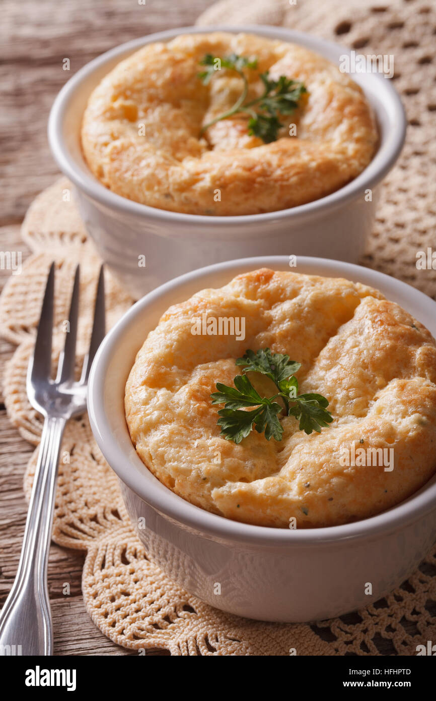 Two baked cheese souffle in a white pot close-up on the table. vertical ...