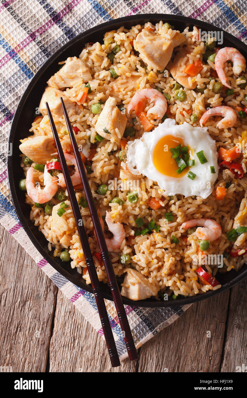 nasi goreng with chicken, shrimp and vegetables close-up vertical view ...