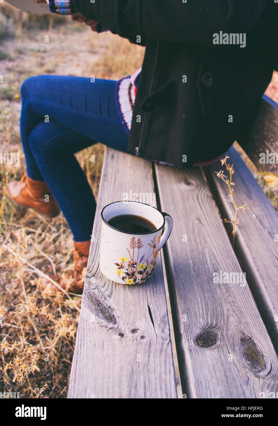 Young woman with a cup of coffee in a wooden bench Stock Photo - Alamy
