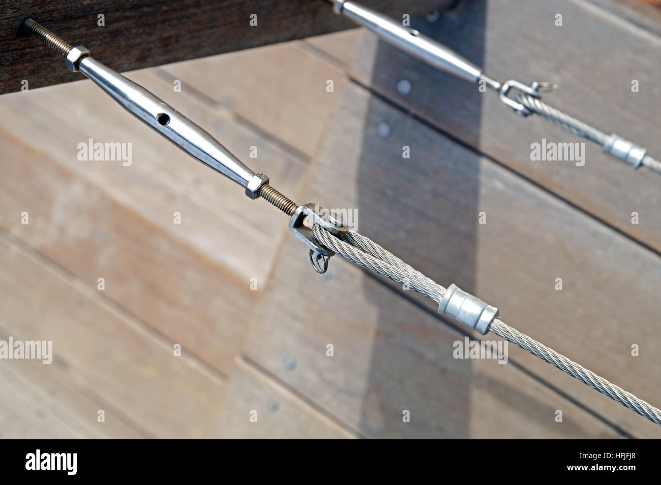 Metal fastening of two steel cables on wood background Stock Photo - Alamy