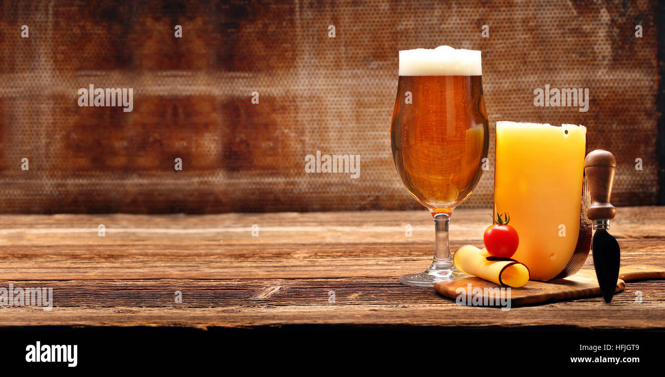 Yellow cheese appetizer and beer on brown vintage background and space ...