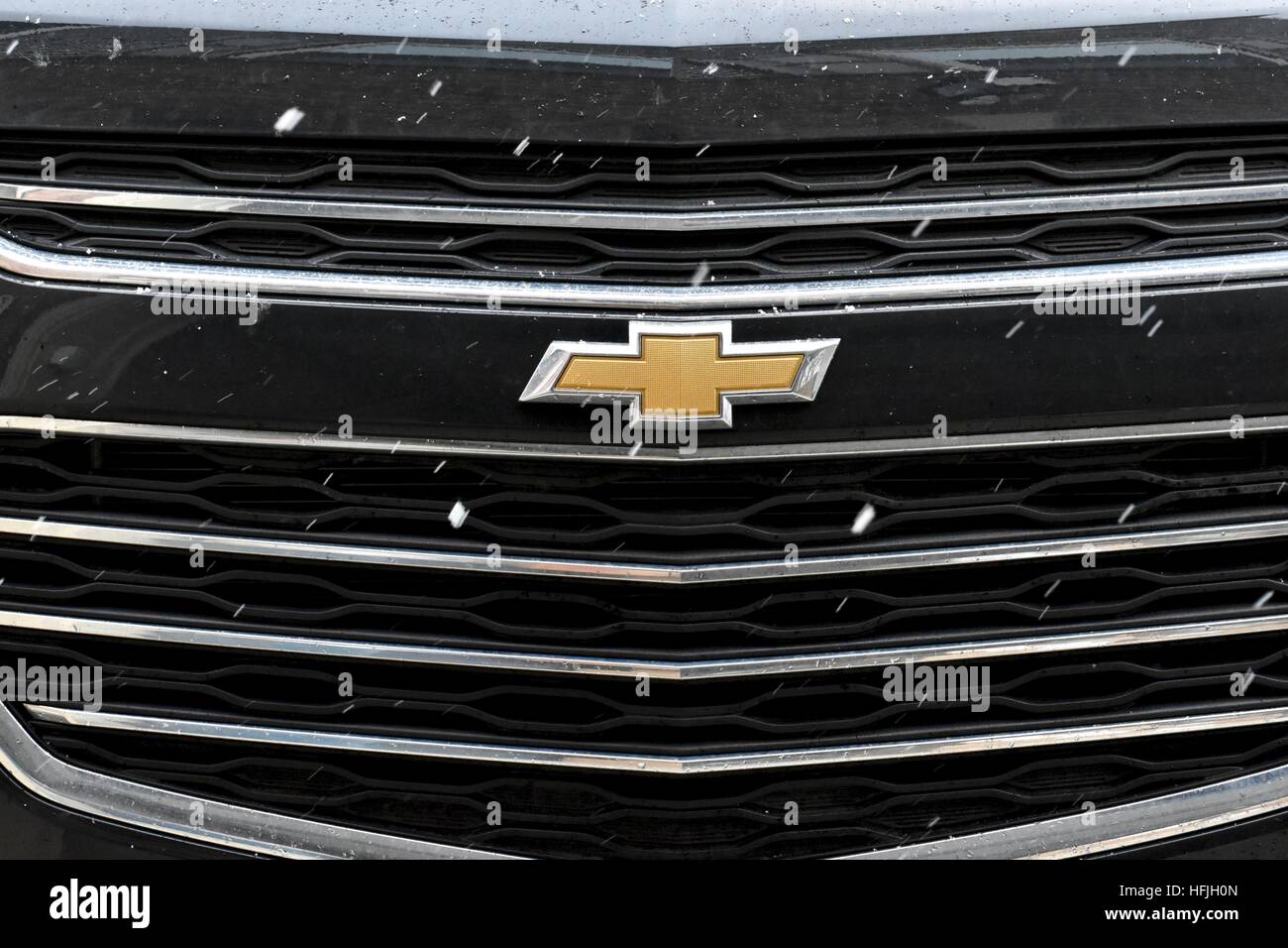 A close up view on the Chevy logo while snowflakes are coming from the ...
