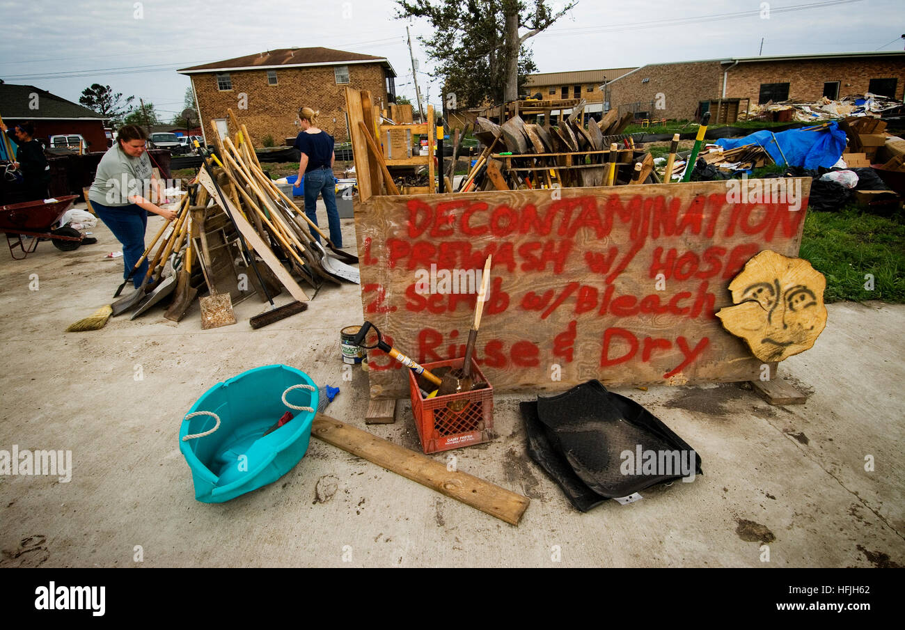 Volunteers in protective gear strip heavily molded drywall and contents ...