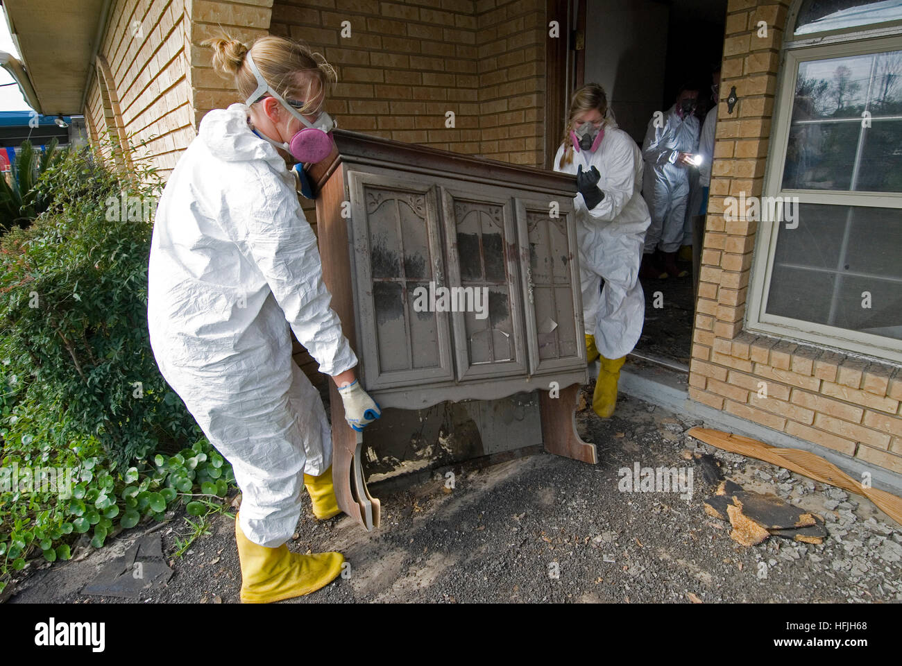 Volunteers in protective gear strip heavily molded drywall and contents ...