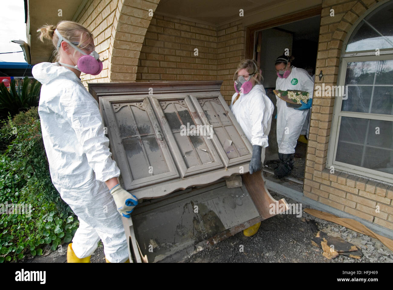 Volunteers in protective gear strip heavily molded drywall and contents ...