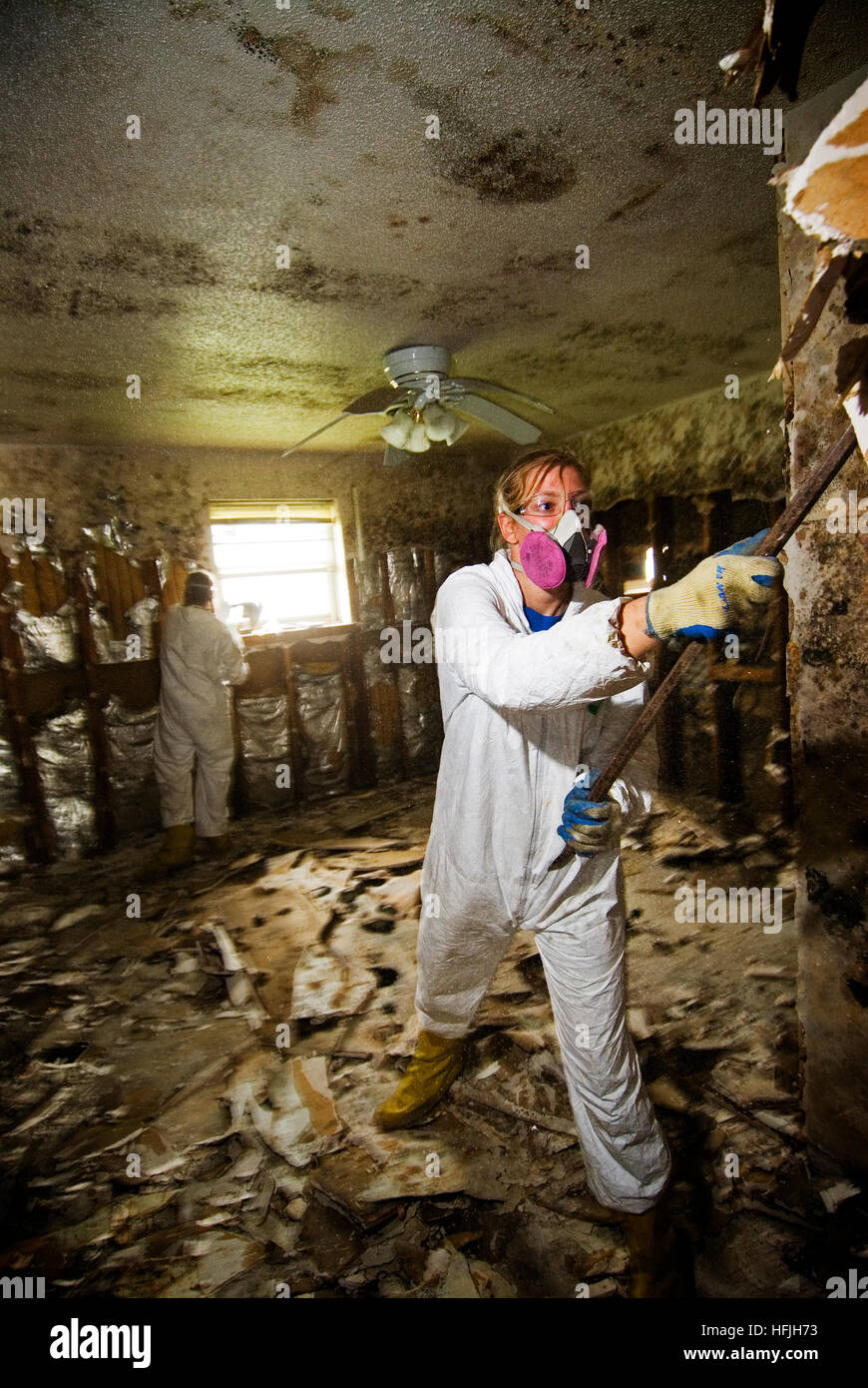 Volunteers in protective gear strip heavily molded drywall and contents ...