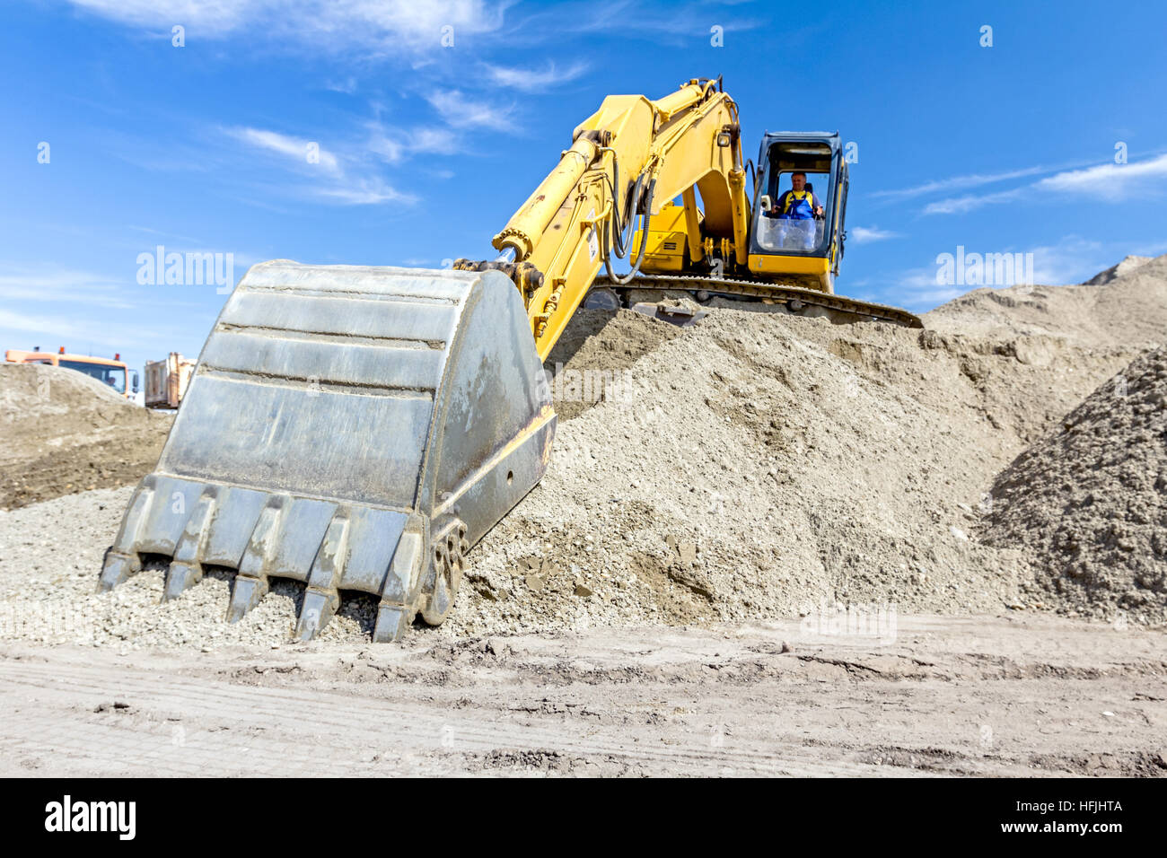 Yellow excavator is making pile of soil by pulling ground up on heap at ...