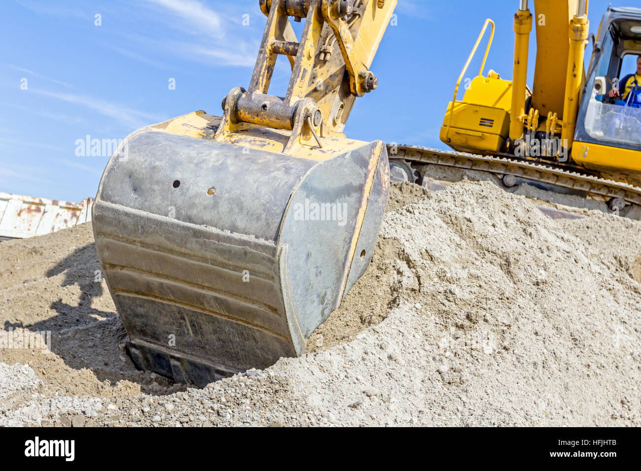 Yellow excavator is making pile of soil by pulling ground up on heap at ...