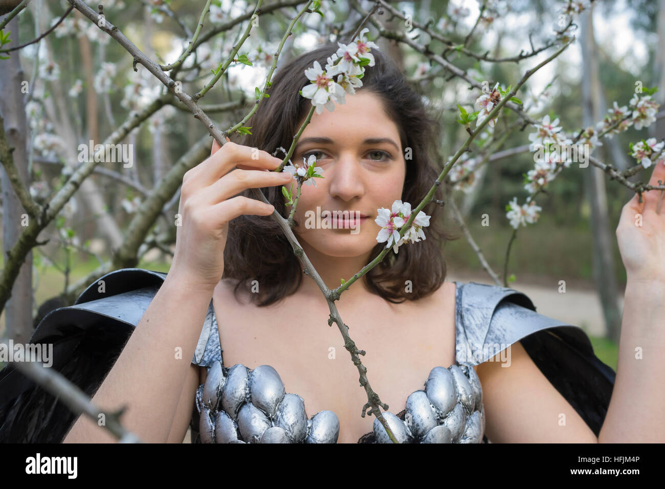 Cute beautiful brunette girl dressed in armor in a grove of cherry ...