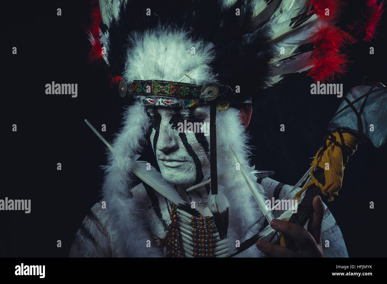 American Indian chief with feather headdress and traditional war ax ...