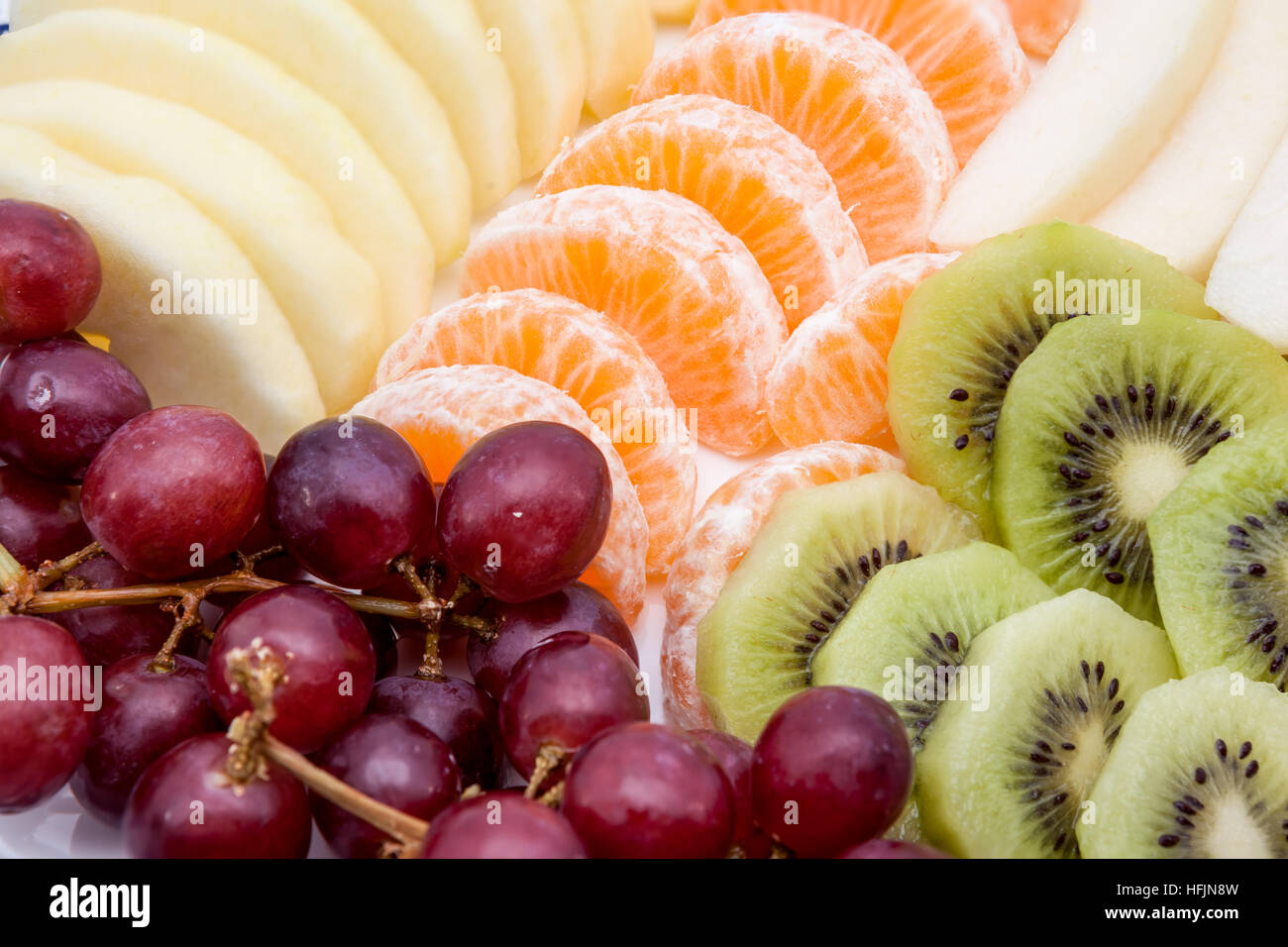 on a square board there is fruit such as mandarin, grapes, kiwi, apple ...