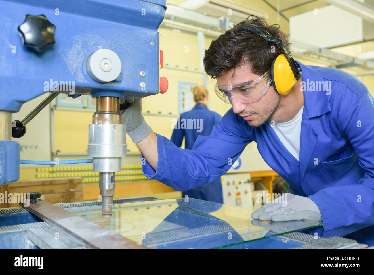 serious trainees focused on drilling metal piece with professional ...