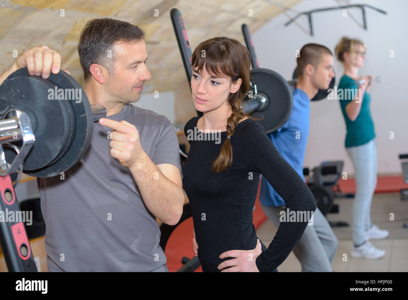 trainer explaining how to use training machine in a gym Stock Photo - Alamy