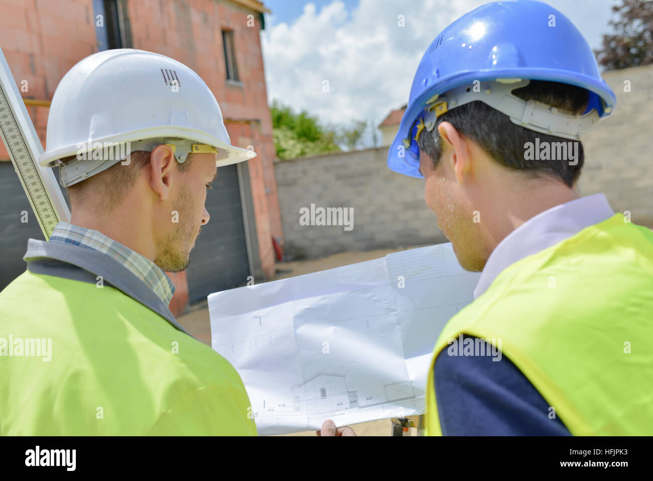 Two men on building site looking at plans Stock Photo - Alamy