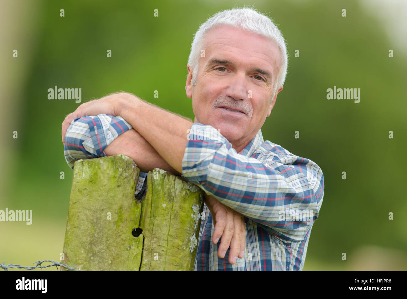 mature man leaning on post Stock Photo - Alamy
