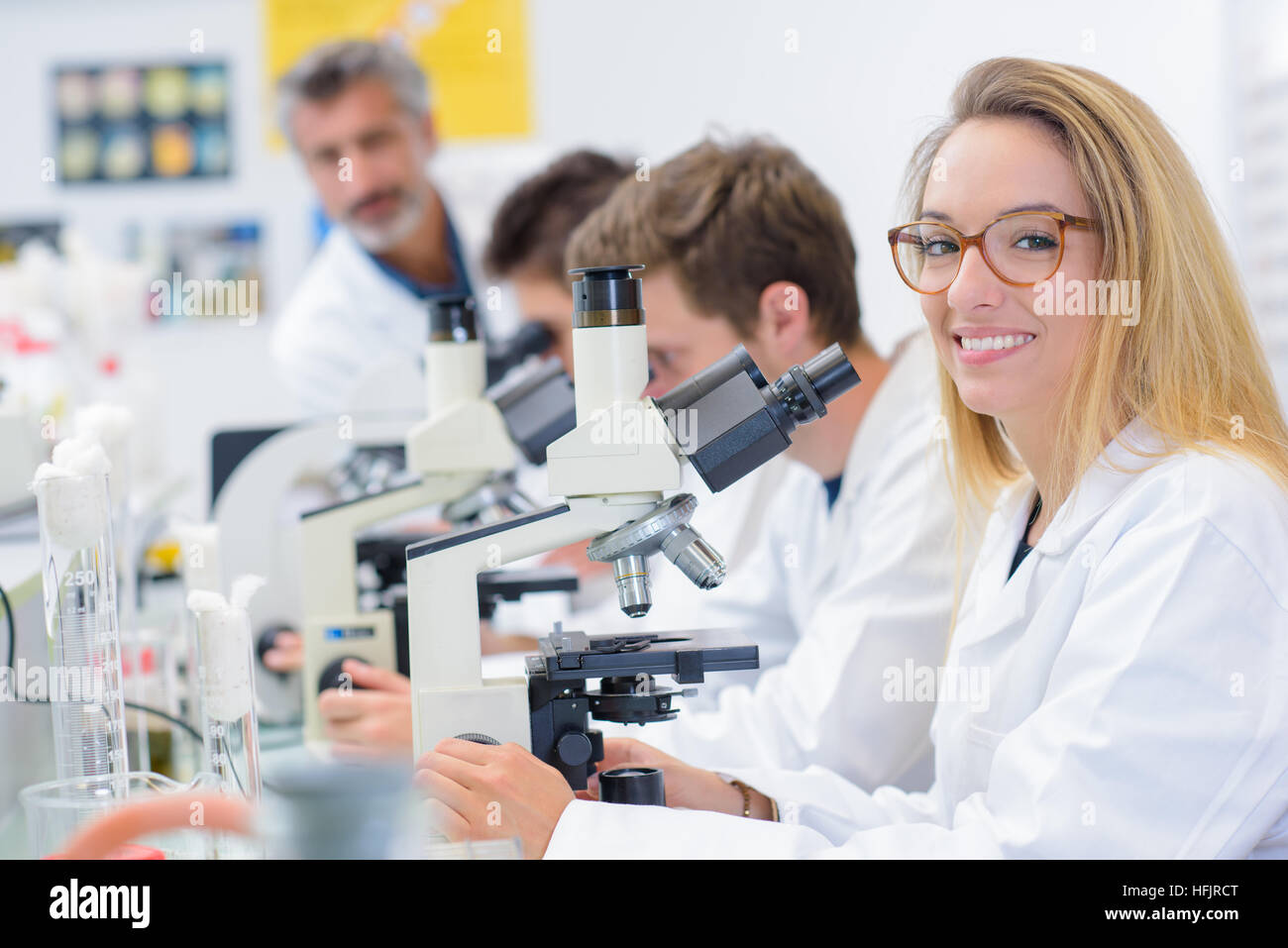 Lady looking up from her microscope, smiling Stock Photo - Alamy