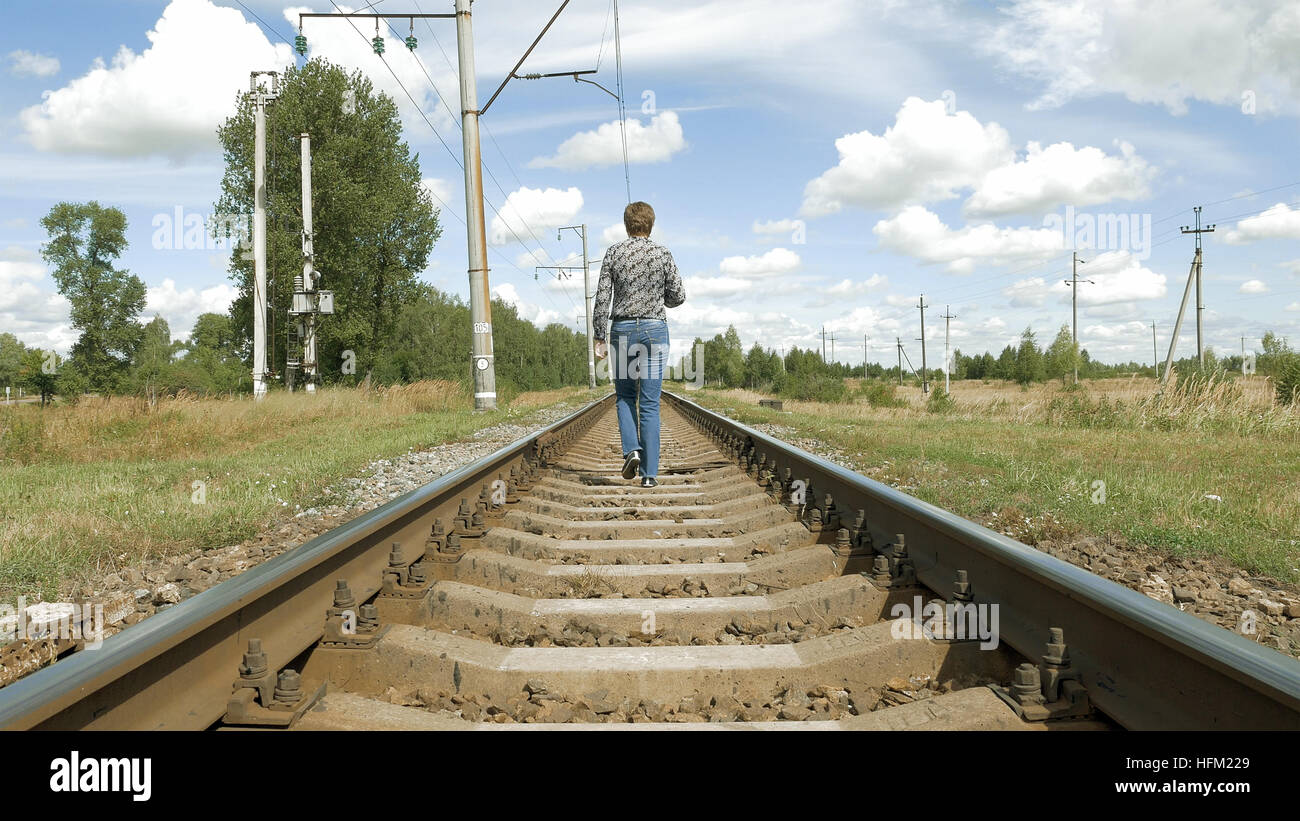 Woman walks along railway tracks in countryside Stock Photo - Alamy