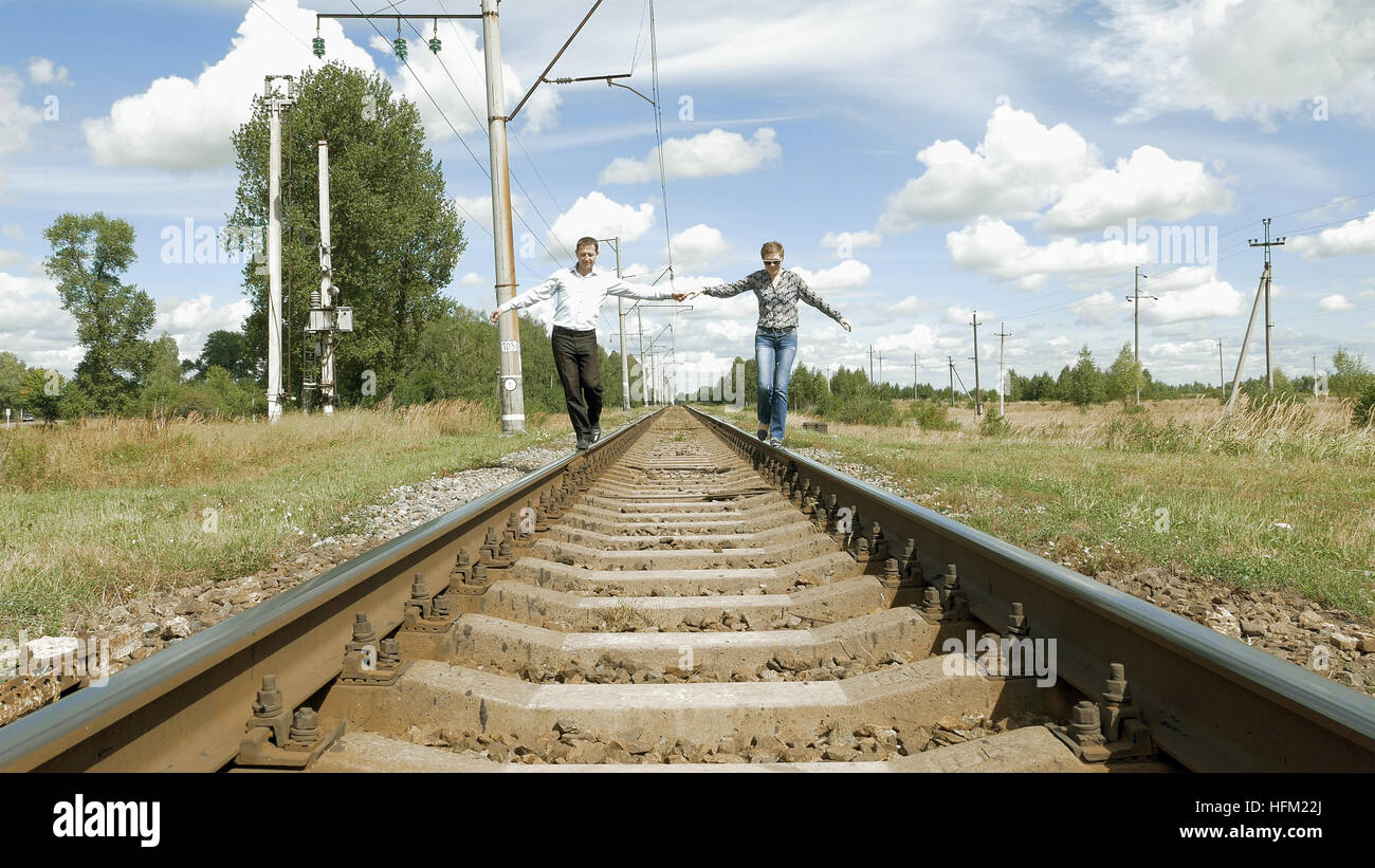 Man and woman holding hands walking along railway Stock Photo - Alamy