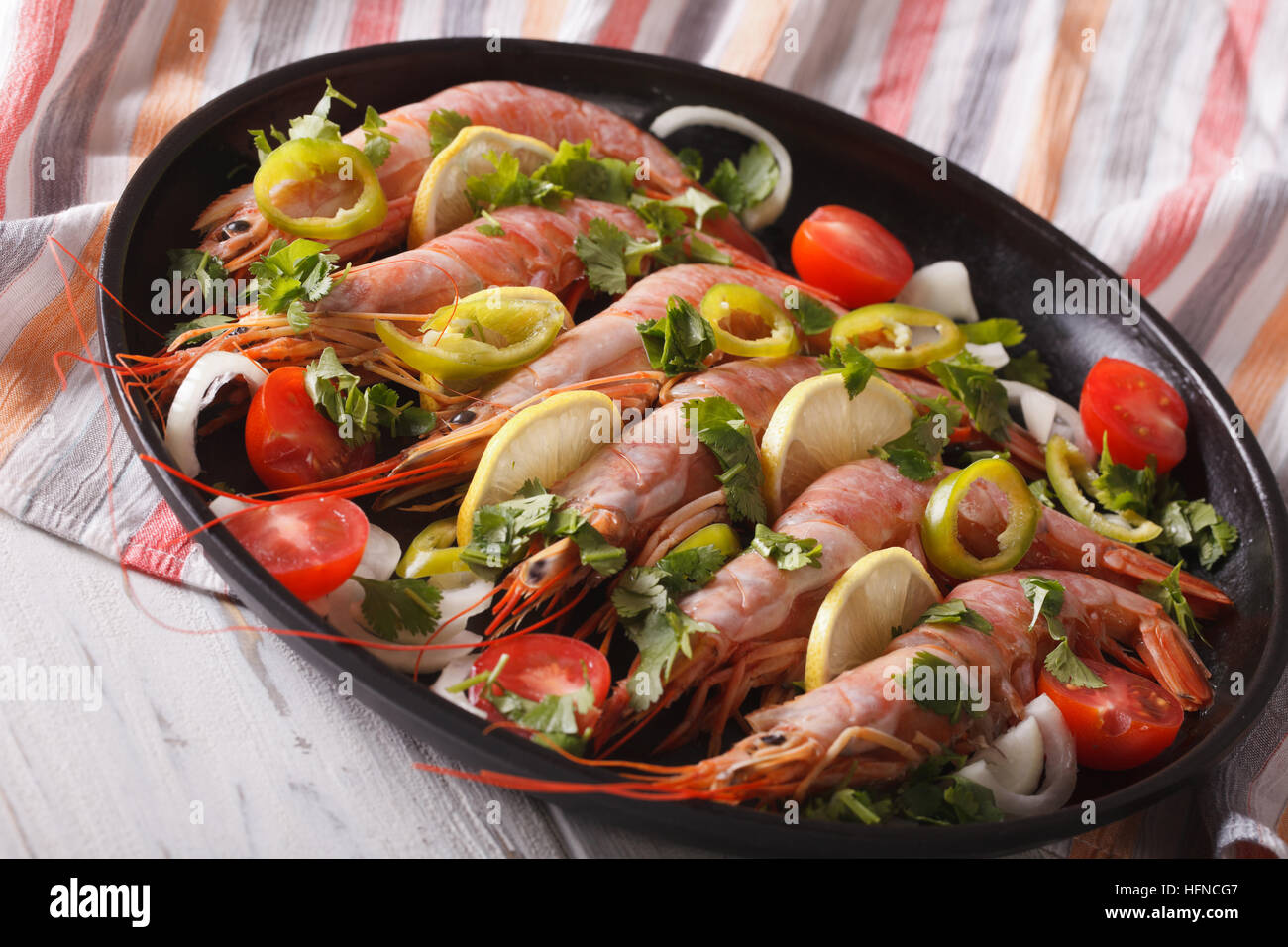 Boiled prawns with chilli, herbs and vegetables close-up on a plate ...