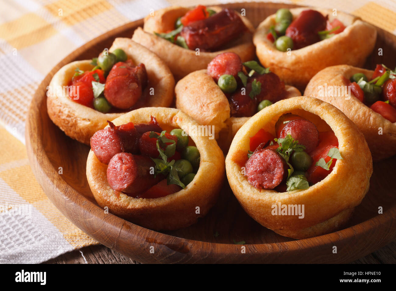 Delicious Yorkshire puddings stuffed with sausage and green peas close ...
