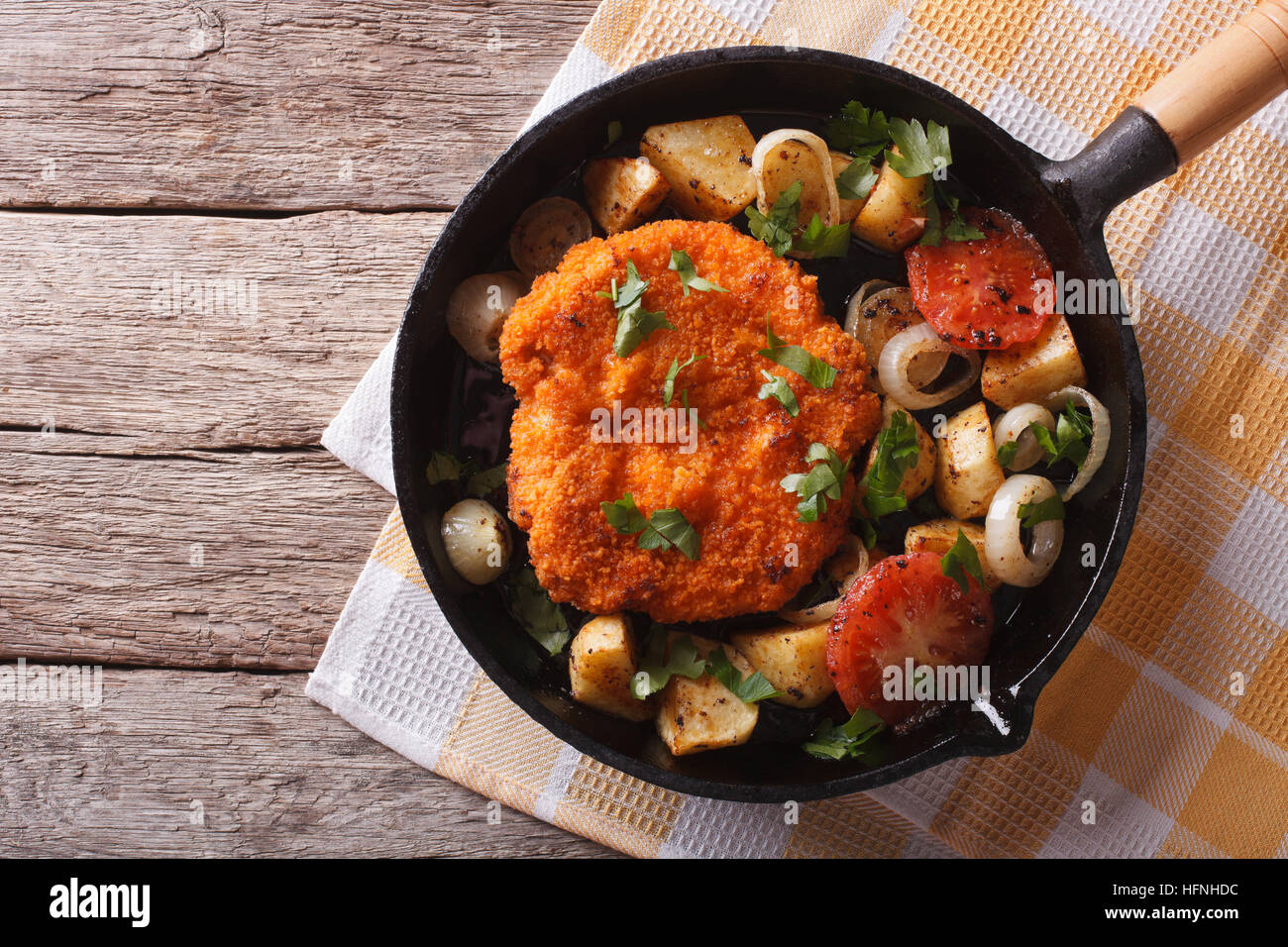 breaded German Weiner schnitzel with fried vegetables in a pan on the ...