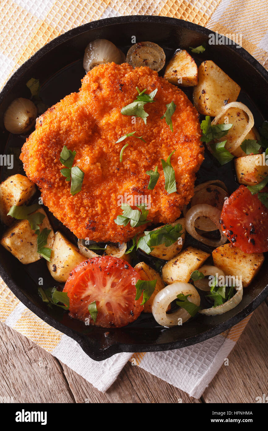 breaded German Weiner schnitzel, fried potatoes in a pan close-up ...