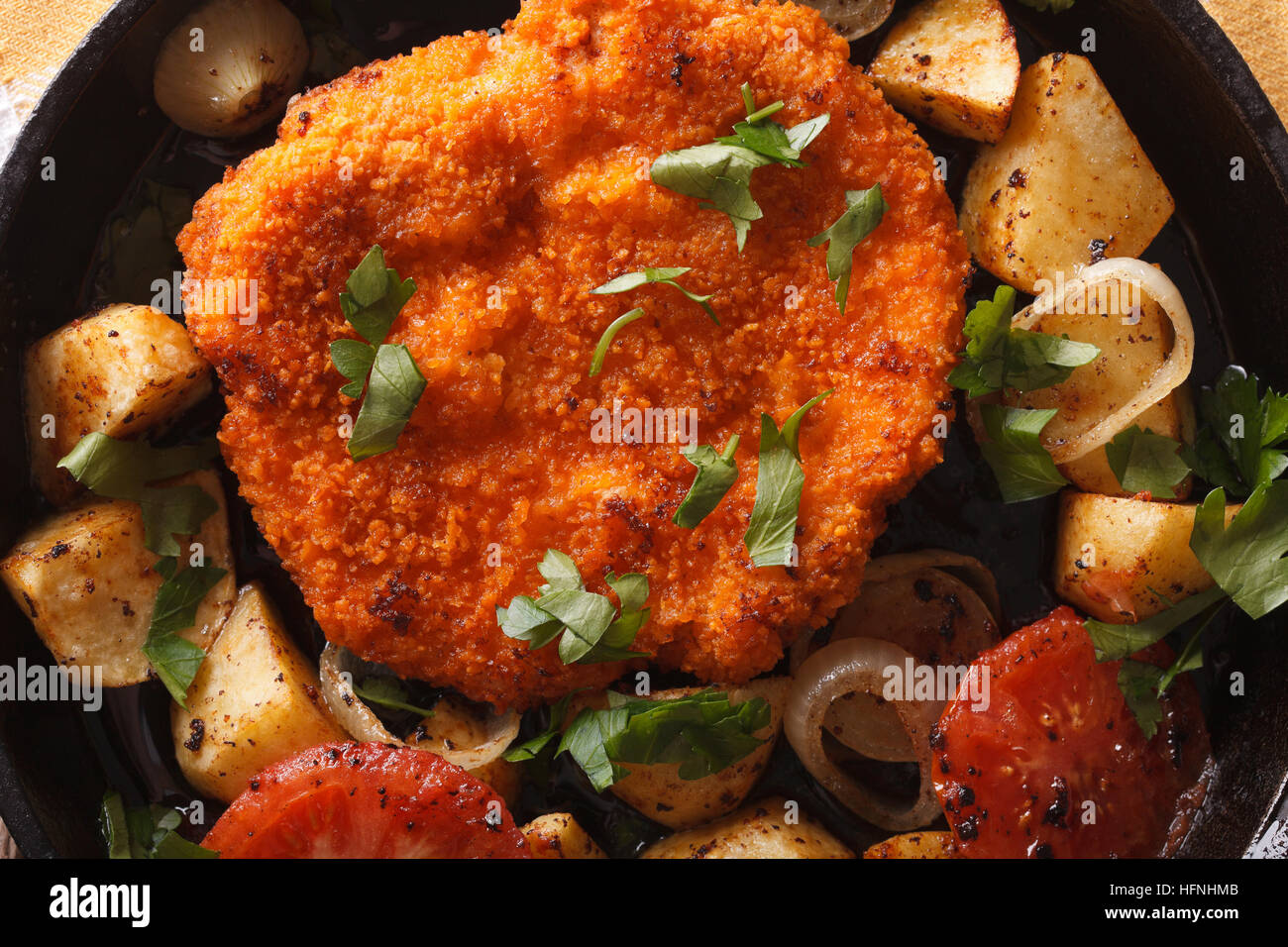 breaded German Weiner schnitzel, fried potatoes in a pan close-up ...