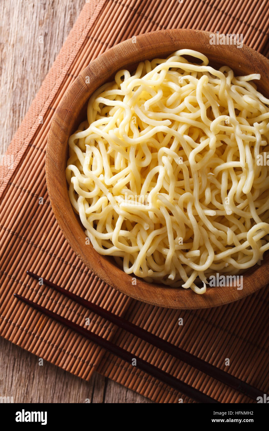 Asian ramen noodles in wooden bowl close-up on the table. vertical top ...
