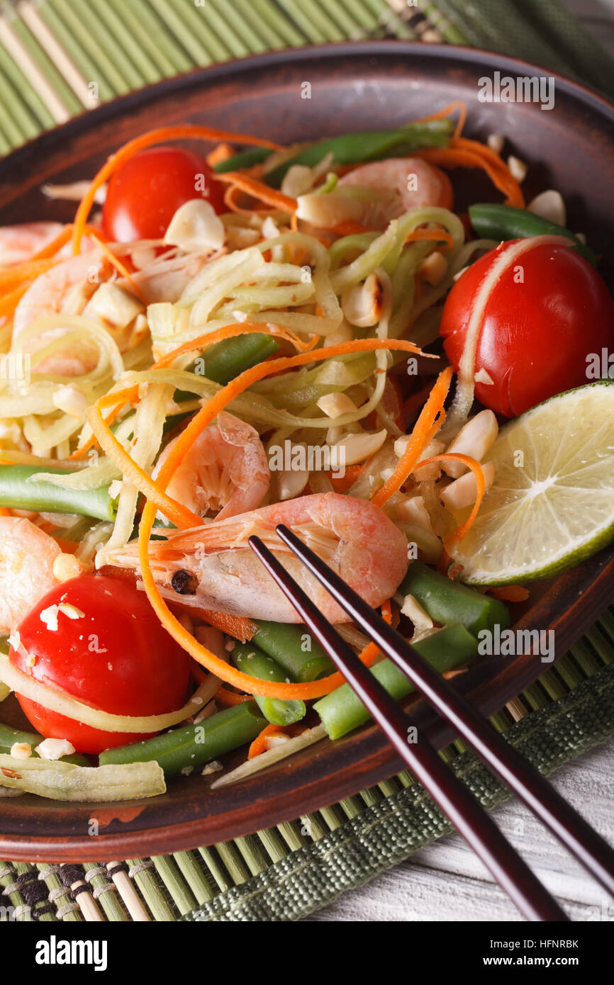 Thai green papaya salad som tam with shrimp close-up on a plate ...