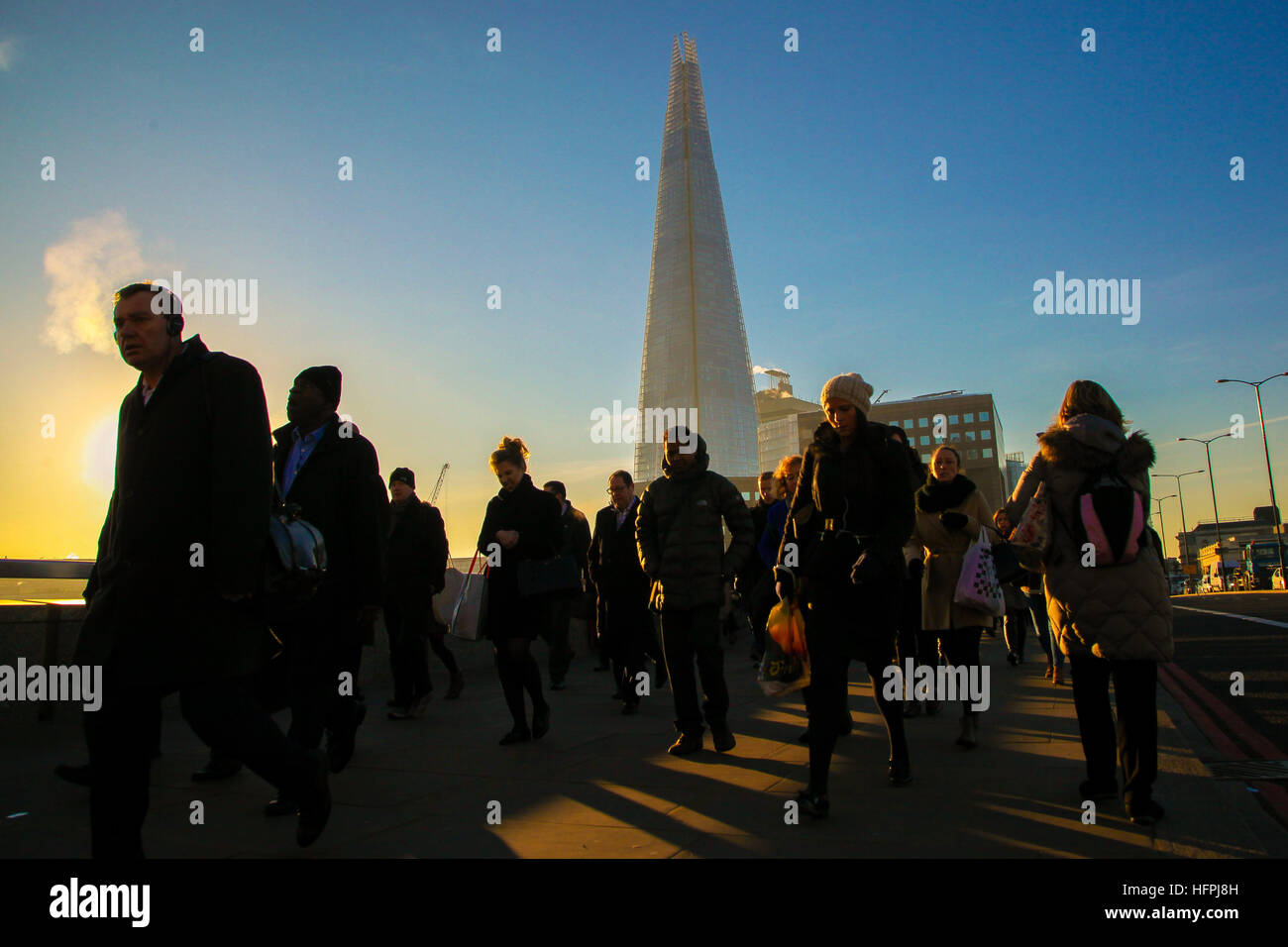 Commuters walk over London Bridge on a cold sunny morning with freezing ...