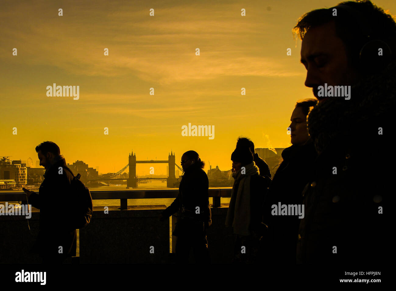 Commuters walk over London Bridge on a cold sunny morning with freezing ...