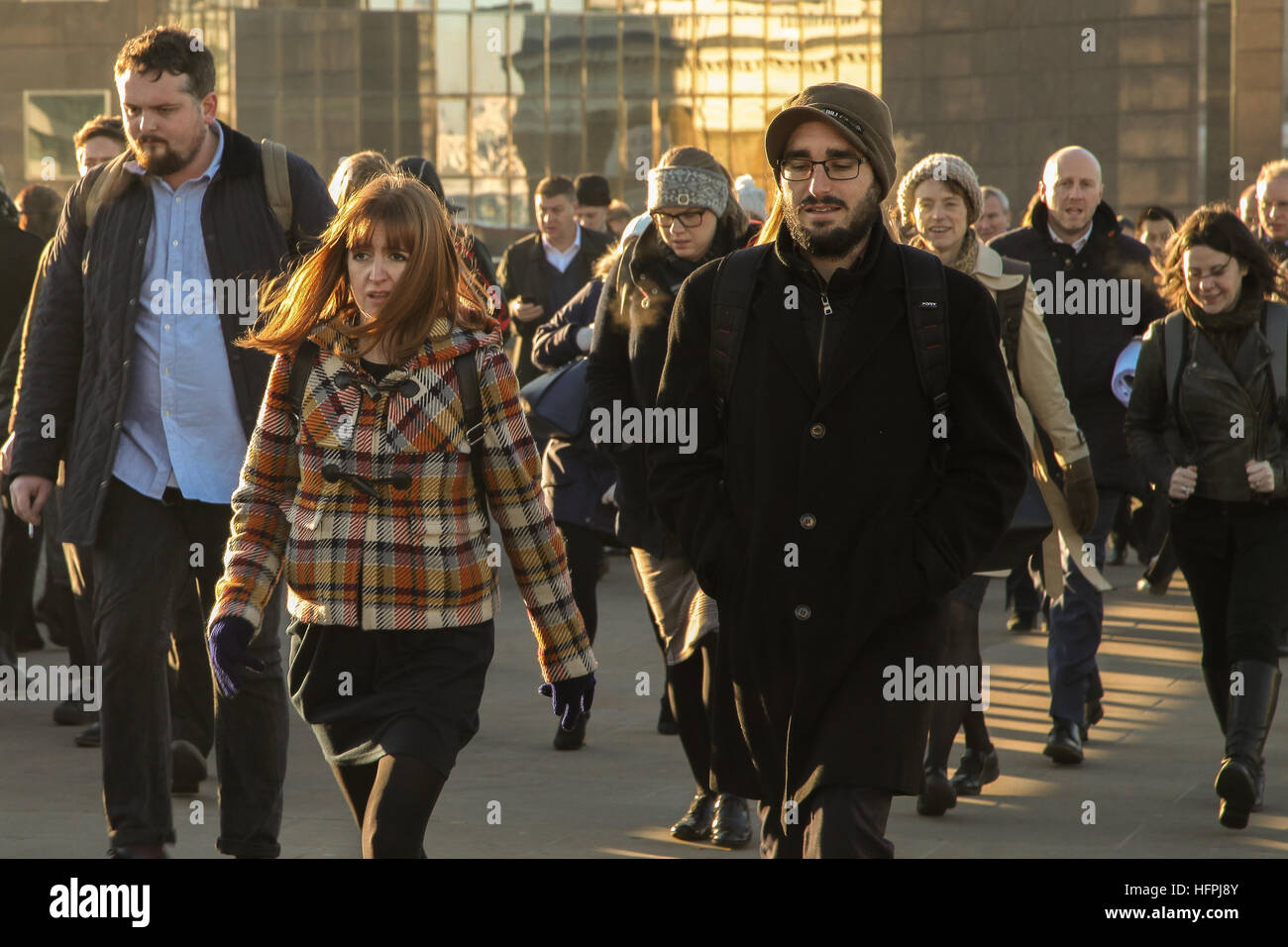 Commuters walk over London Bridge on a cold sunny morning with freezing ...