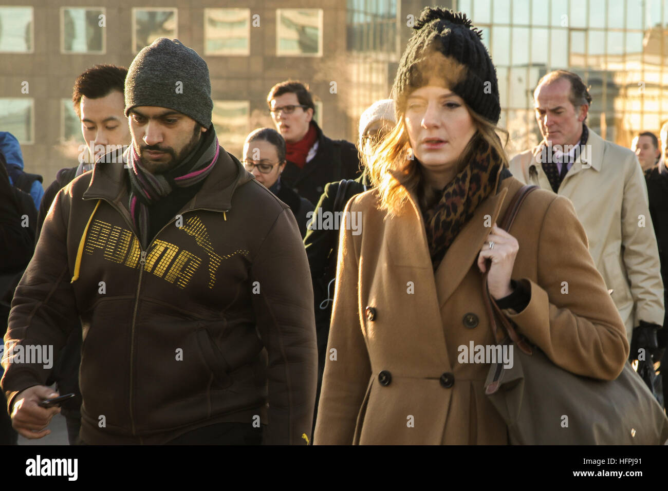 Commuters walk over London Bridge on a cold sunny morning with freezing ...
