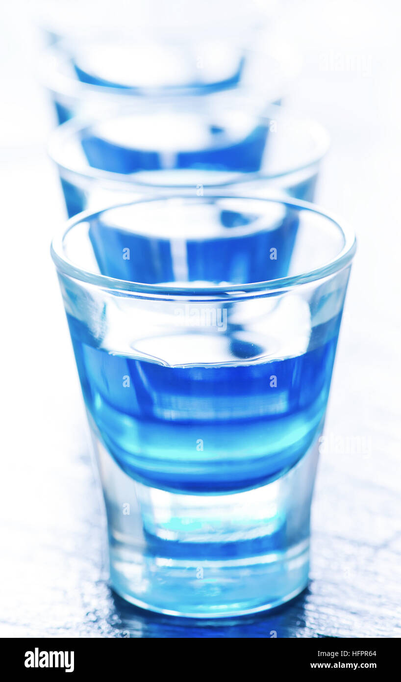blue alcoholic drink into small glasses on a table Stock Photo - Alamy