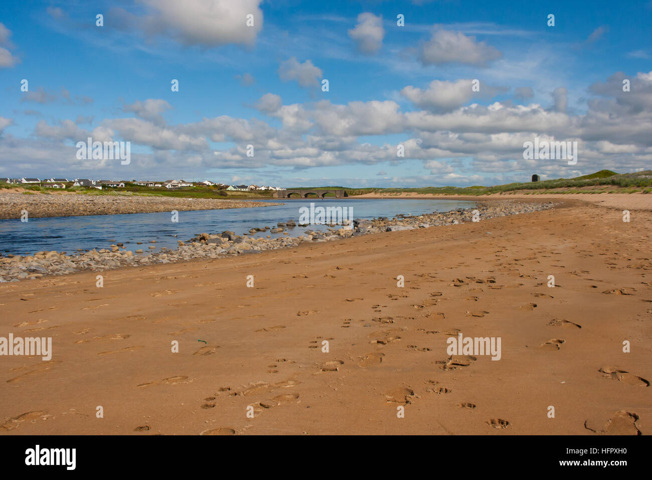 Sandy beach with rocks on the west coast of Ireland with a small river ...
