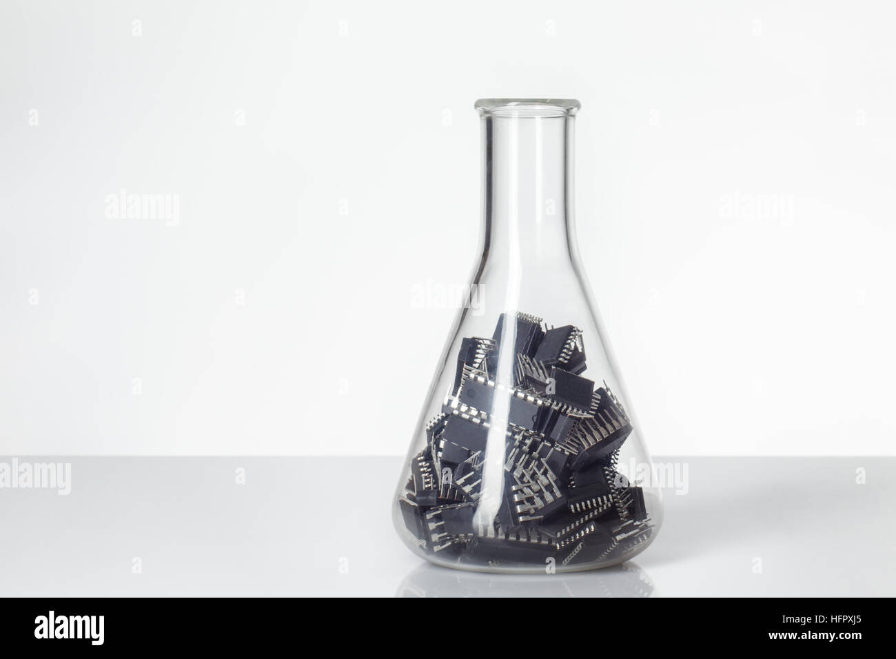 Conical flask holding computer chips inside shot in the studio on white ...