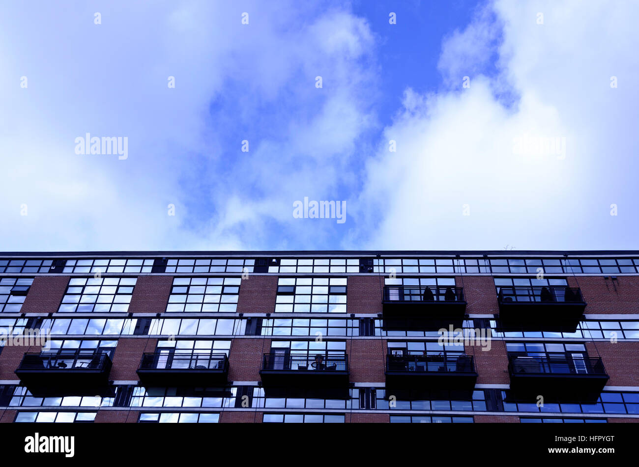 Looking up at a modern loft condominium with the sky and clouds ...