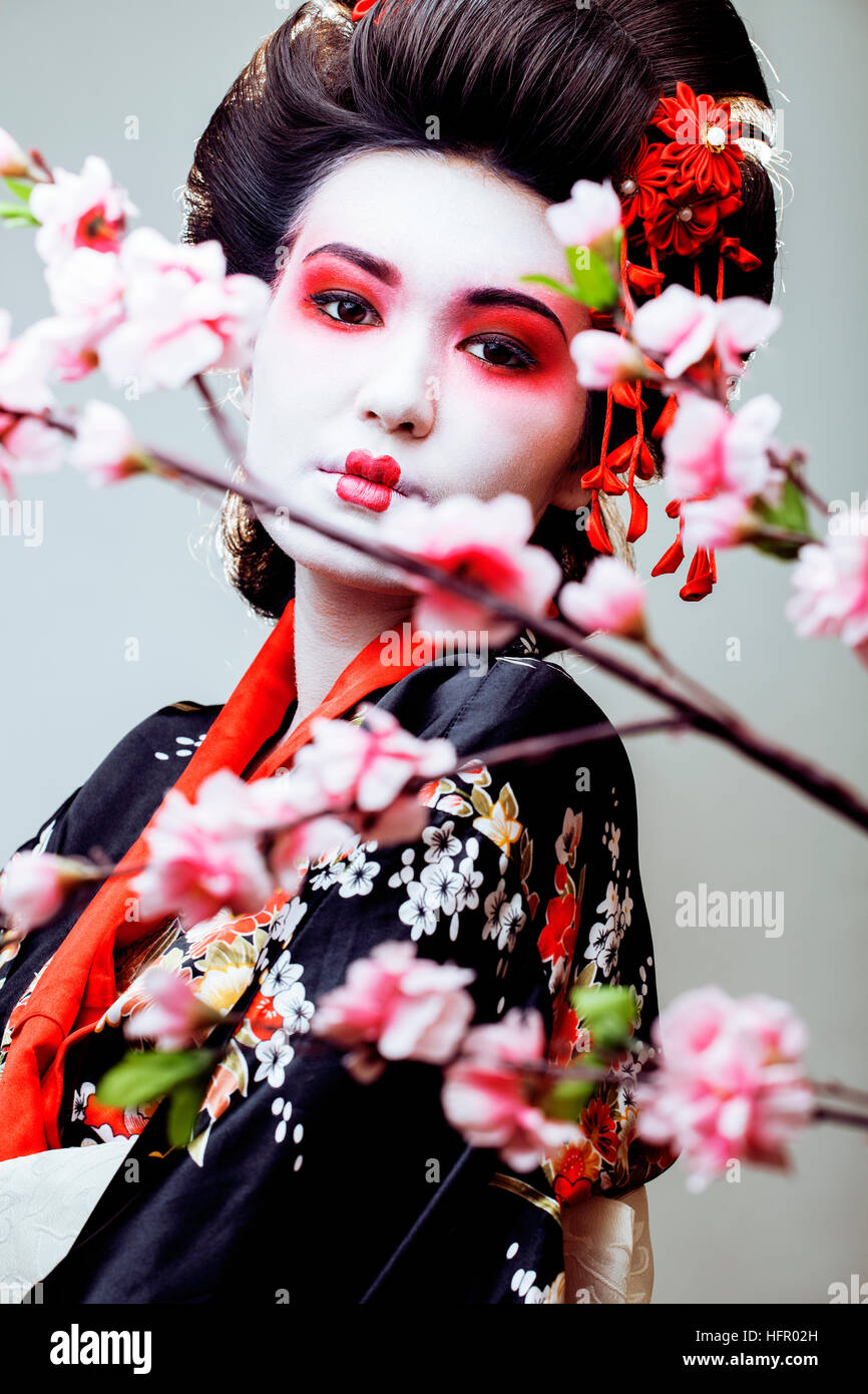 young pretty geisha in black kimono among sakura, asian ethno Stock ...