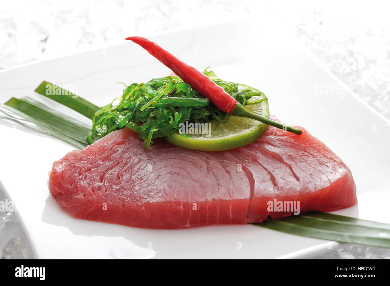 Raw tuna with algae, lime slice, chili pepper and leek Stock Photo - Alamy