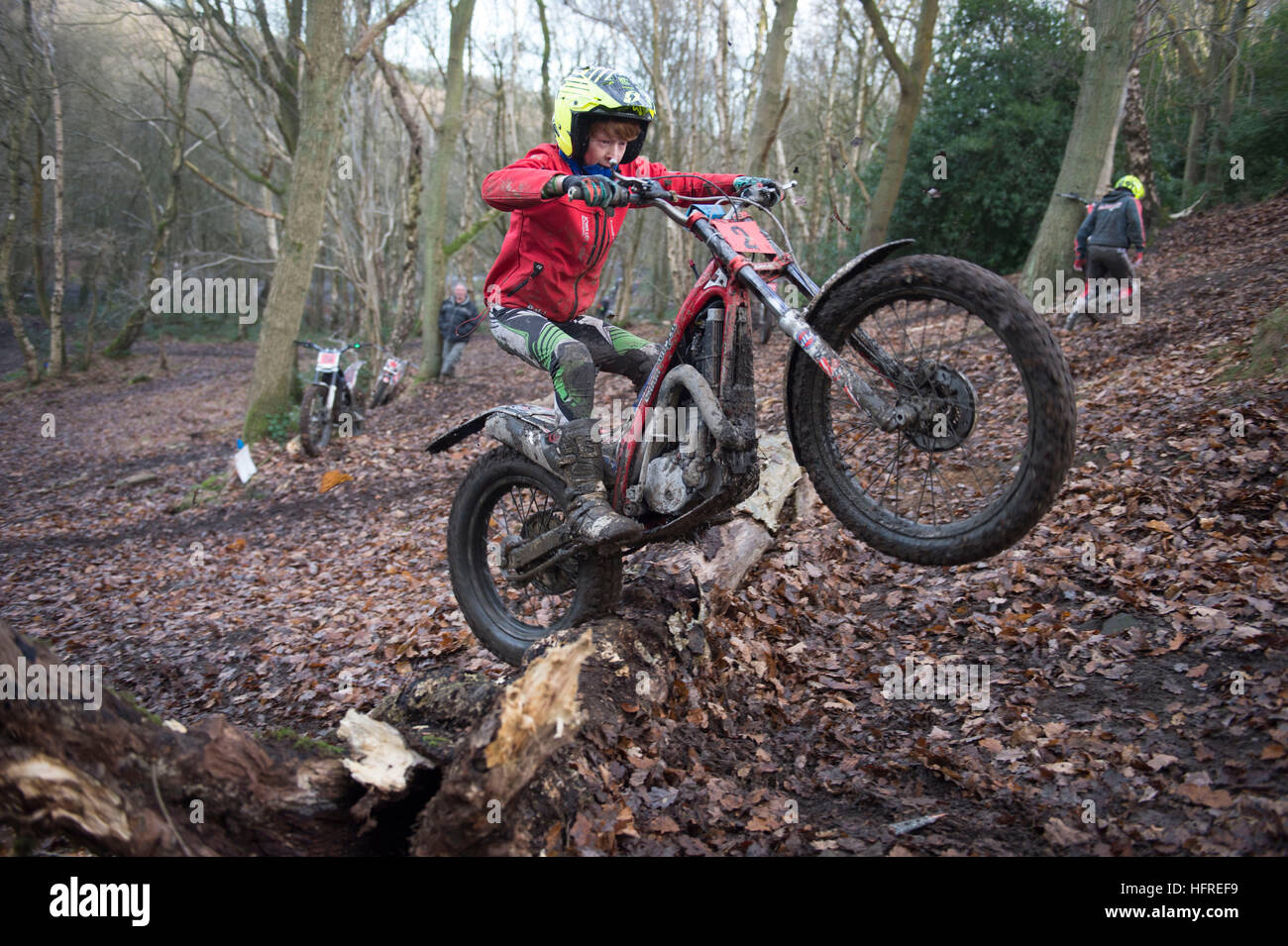 A motorcycle trials rider clears a log as part of a woodland section ...