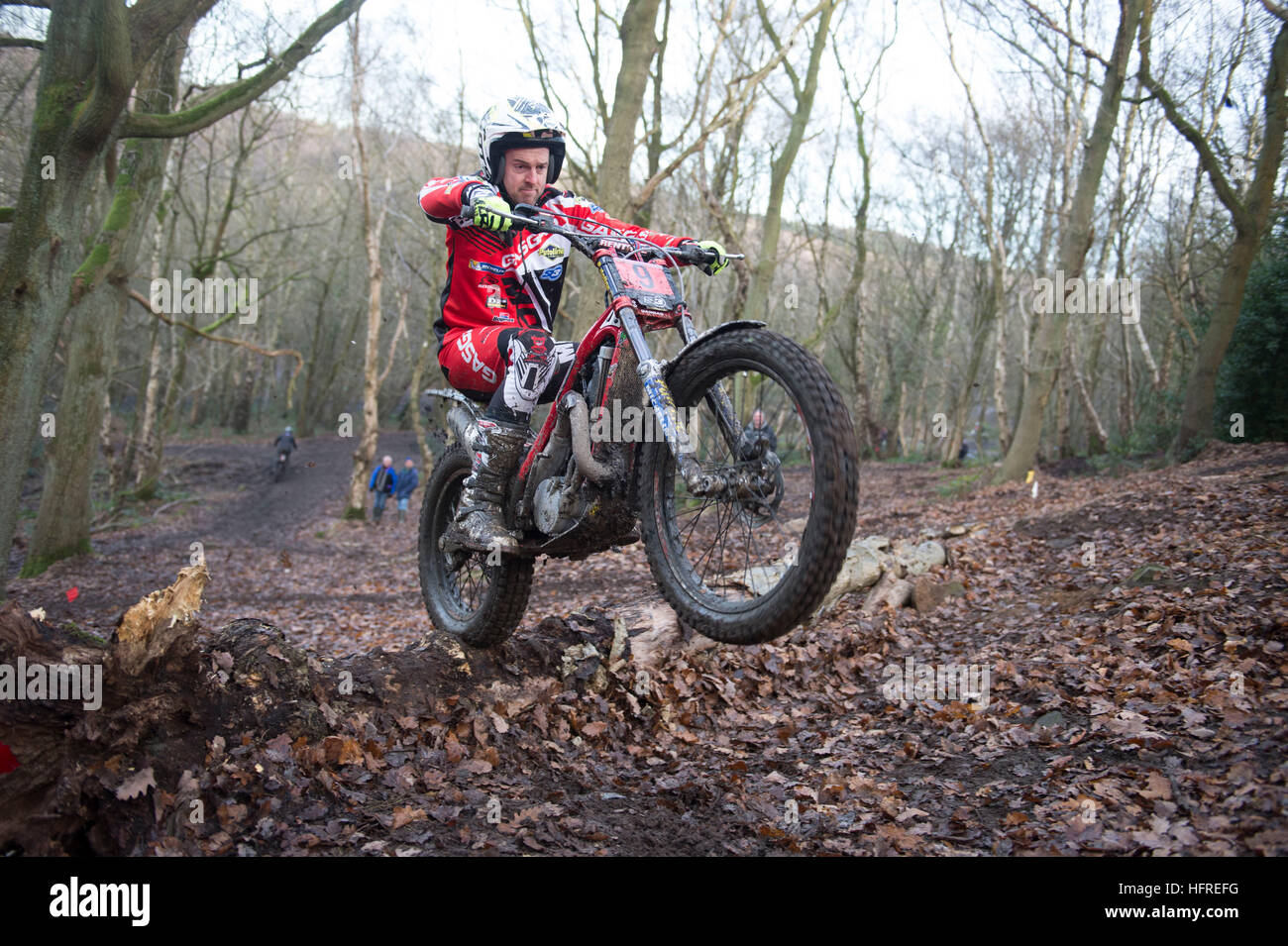 A motorcycle trials rider clears a log as part of a woodland section ...