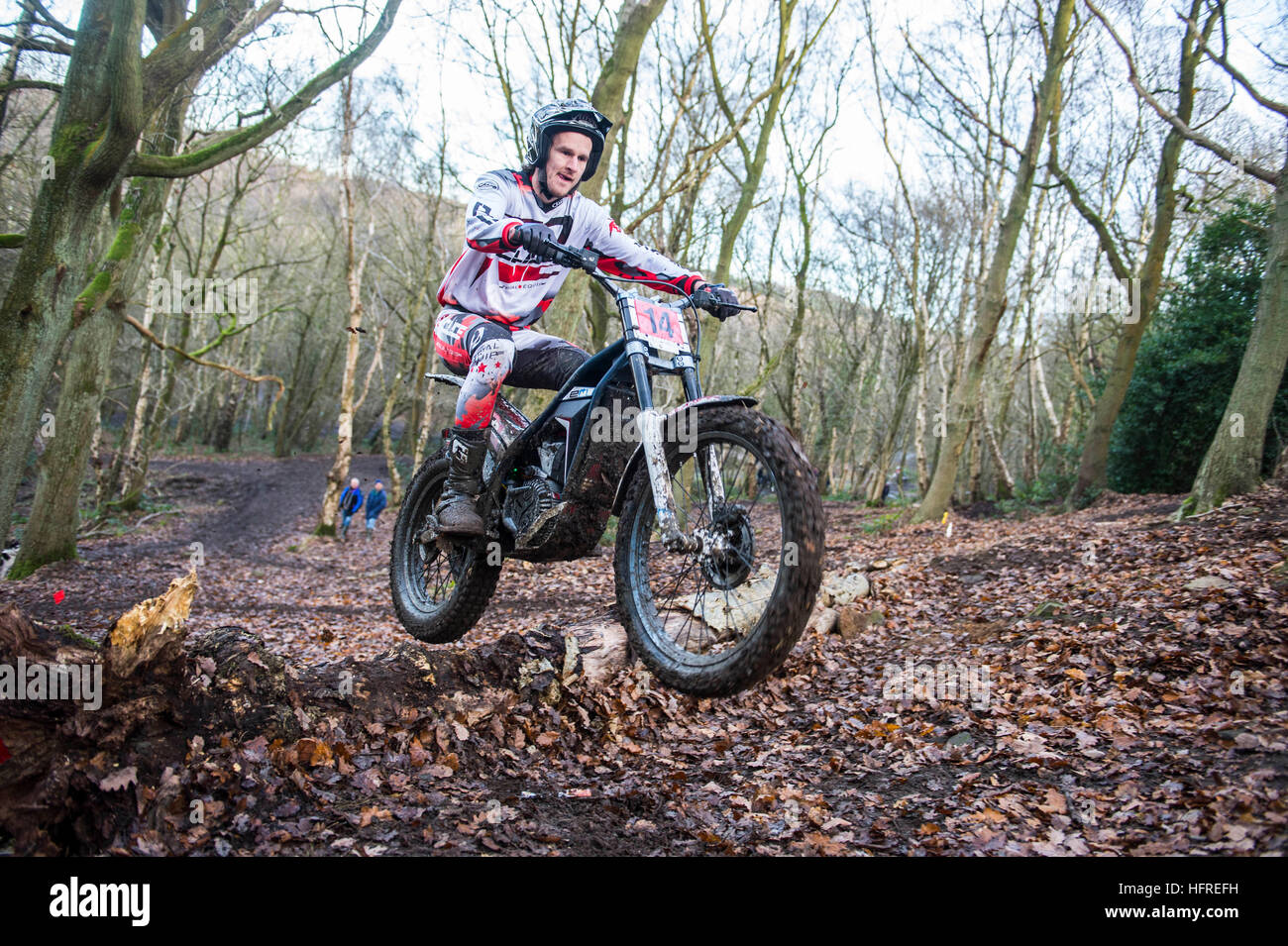A motorcycle trials rider clears a log as part of a woodland section ...