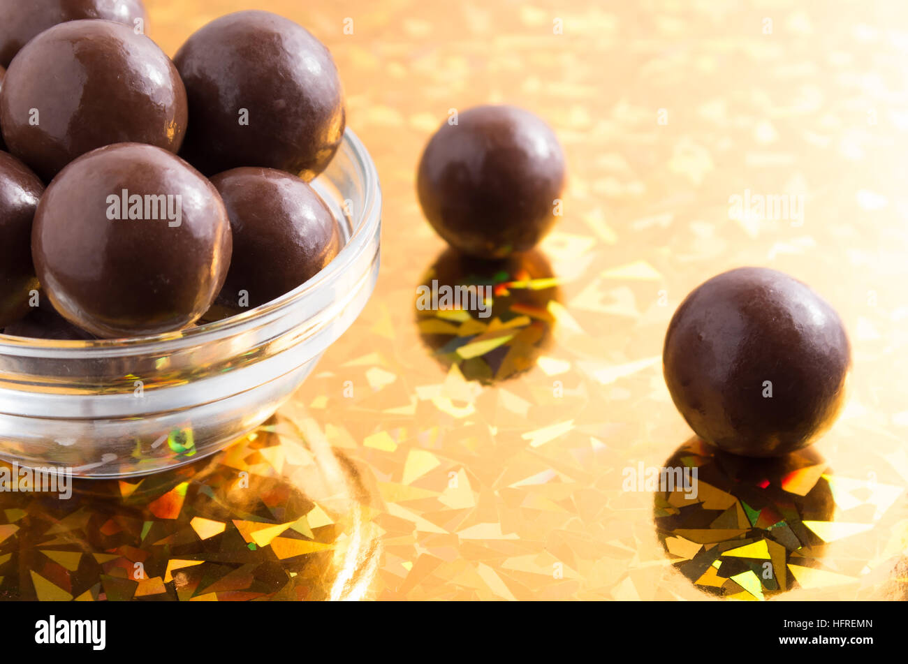 Round chocolate candy in small glass cup on colorful background close ...