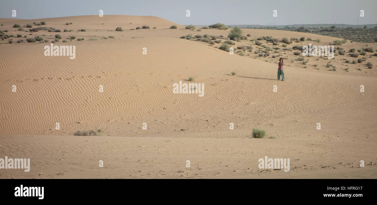 A lone child with a staff among the sand dunes looks into the distance ...