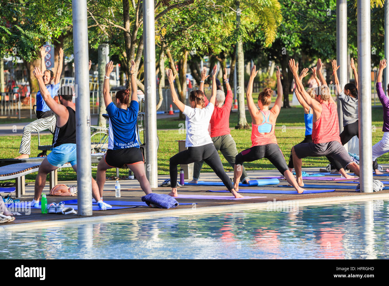 A mixed group of men and women in a yoga class beside an outdoor ...