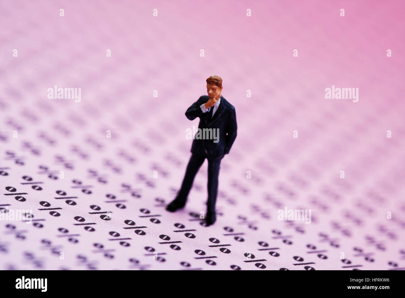 Business manager placed on top of percent symbols printed on pink paper ...